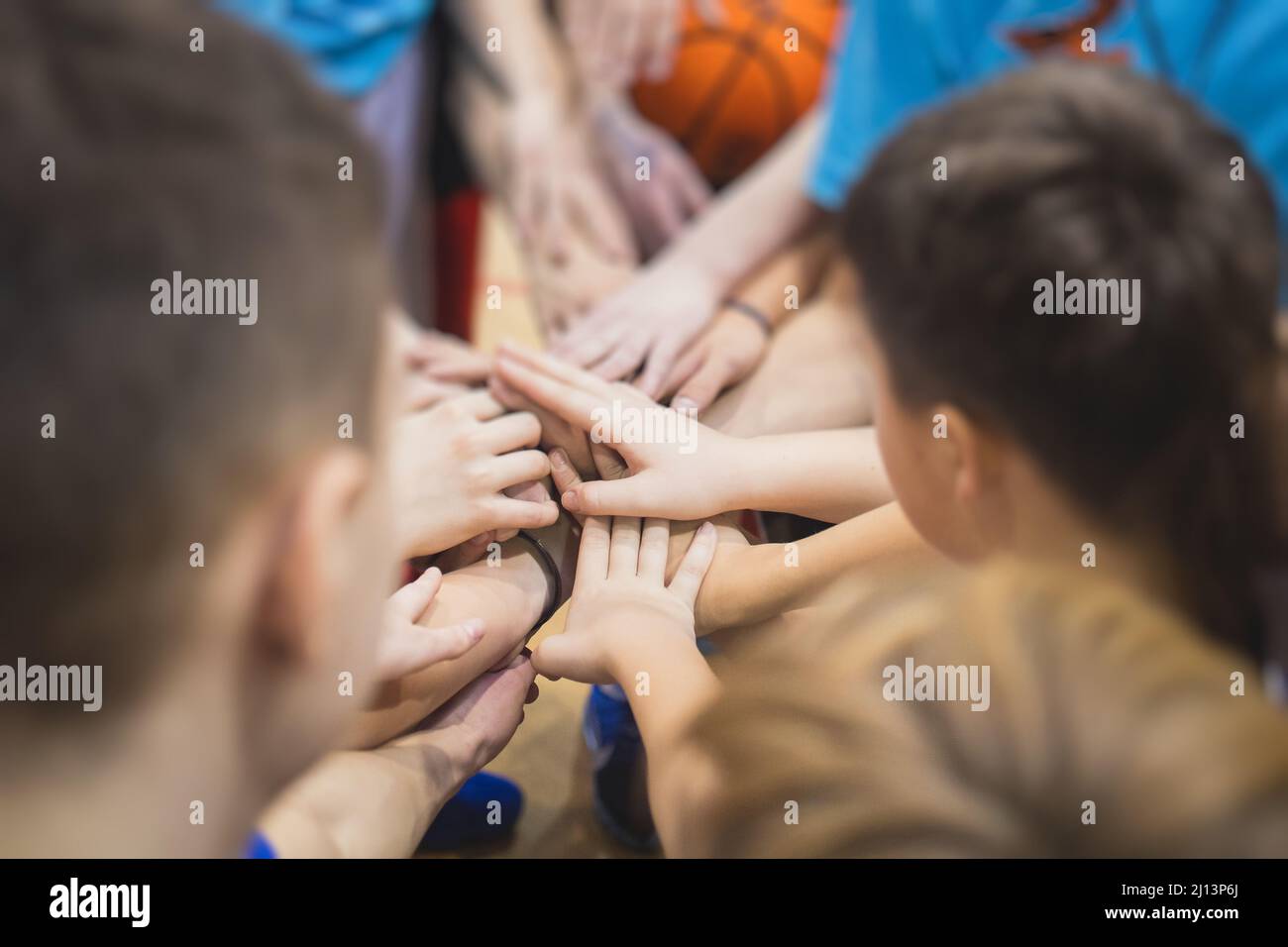 Team of kids children basketball players stacking hands in the court ...
