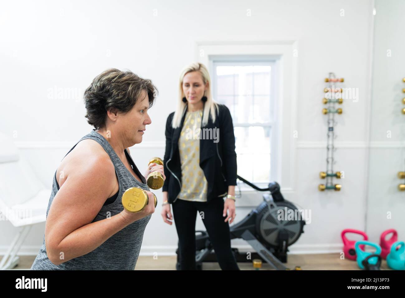 A female personal trainer helping a client exercise, train, and build ...