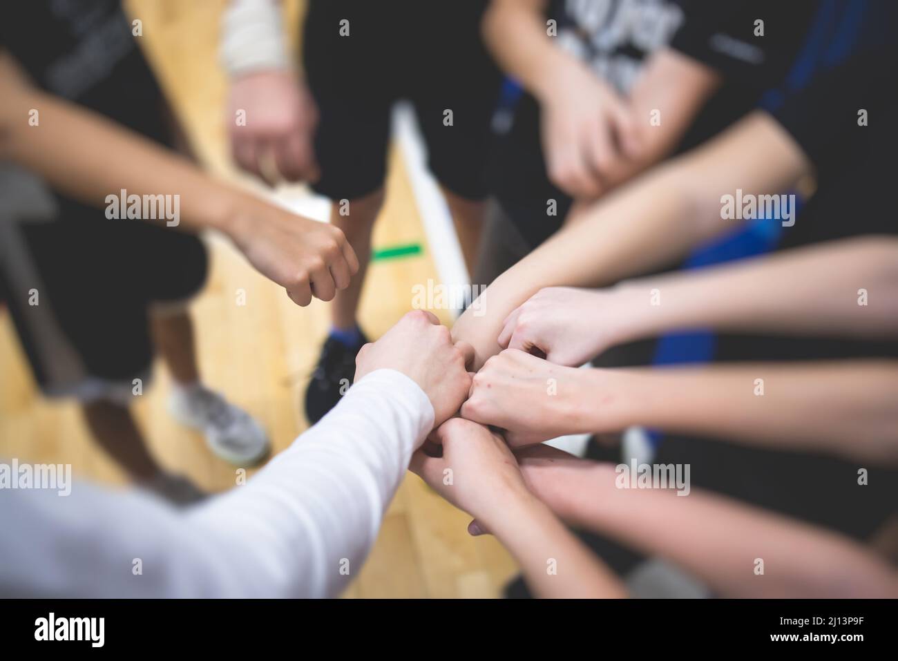 Team of kids children basketball players stacking hands in the court ...