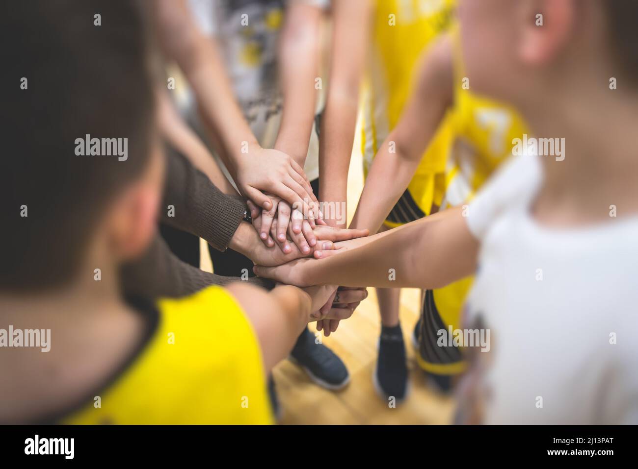 Team of kids children basketball players stacking hands in the court ...