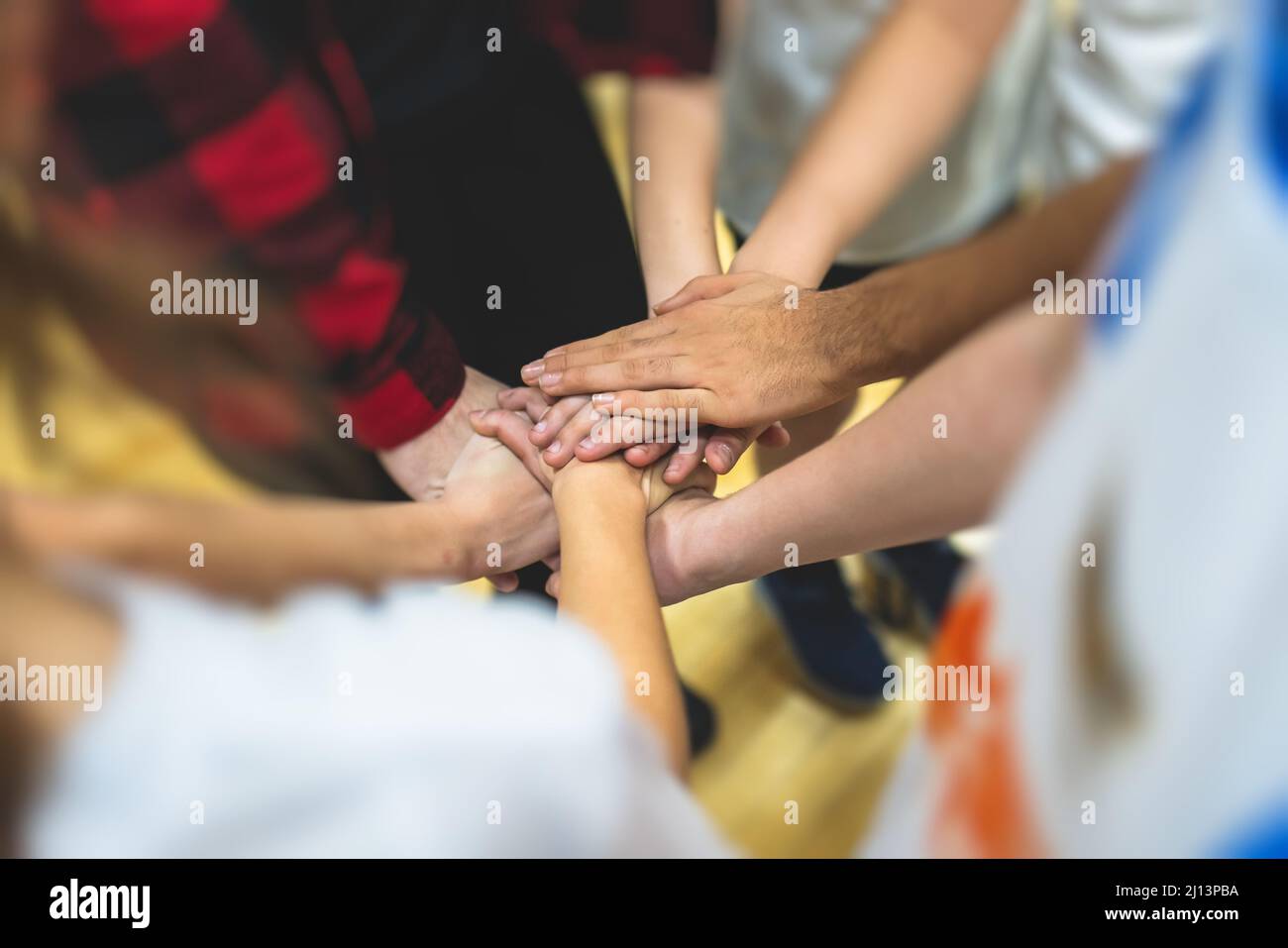 Team of kids children basketball players stacking hands in the court ...