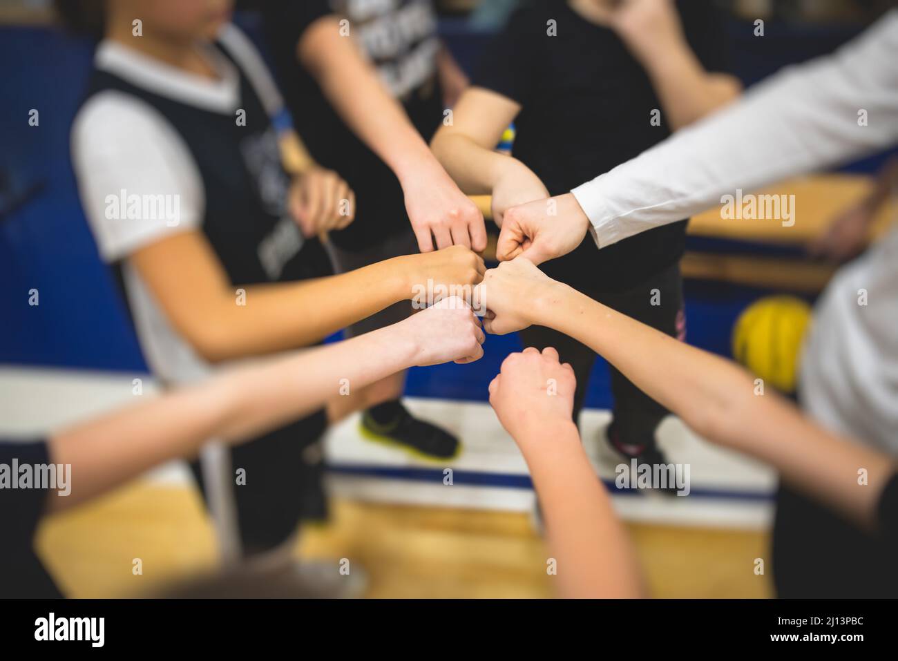 Team of kids children basketball players stacking hands in the court ...