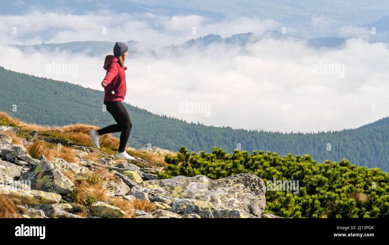 Woman is climbing a mountain ridge. Woman going through a stone valley ...