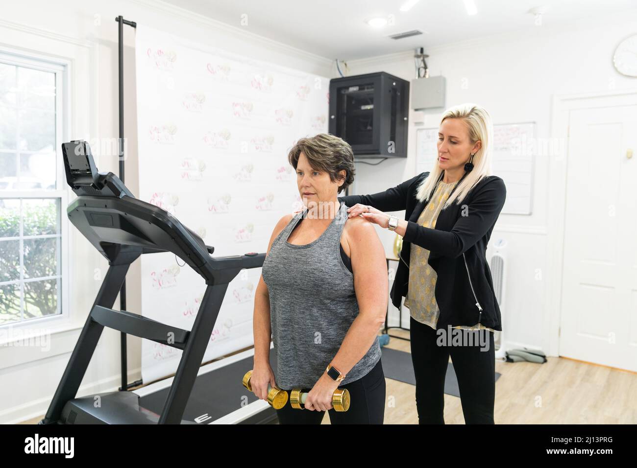 A female personal trainer helping a client exercise, train, and build ...