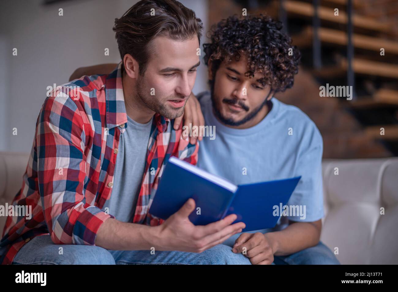 Two men involved in reading a book Stock Photo - Alamy
