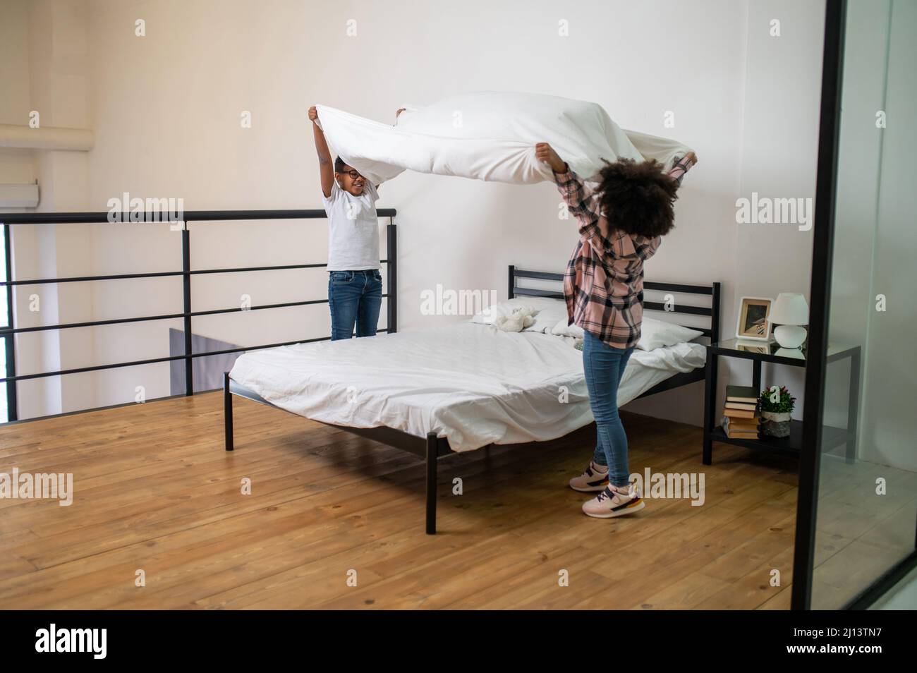 Children raising hands high with sheet over bed Stock Photo - Alamy