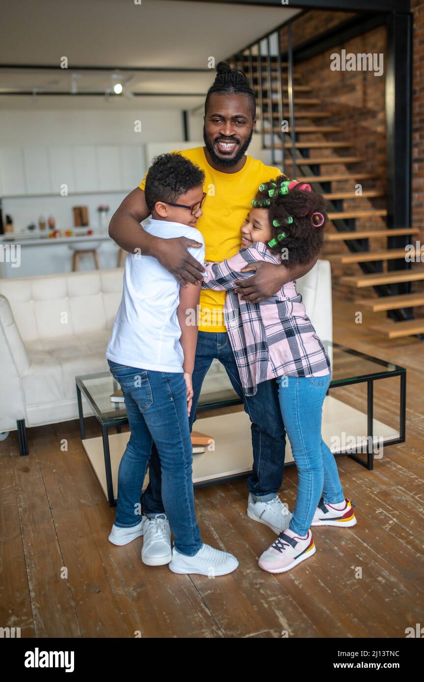 Man hugging children standing in room Stock Photo - Alamy