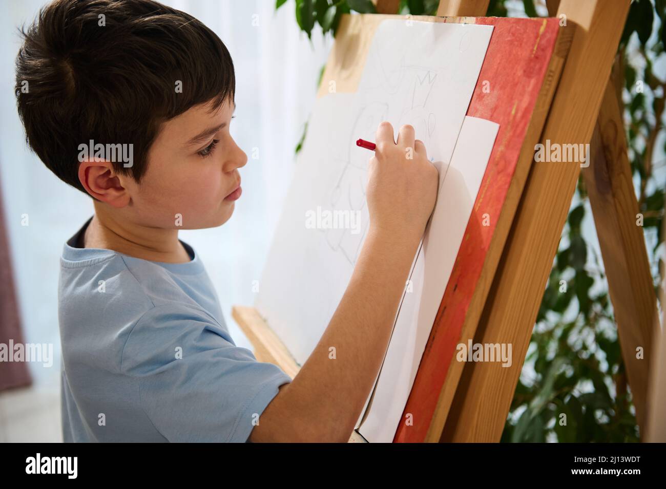 Handsome concentrated Caucasian school boy drawing on canvas on a ...