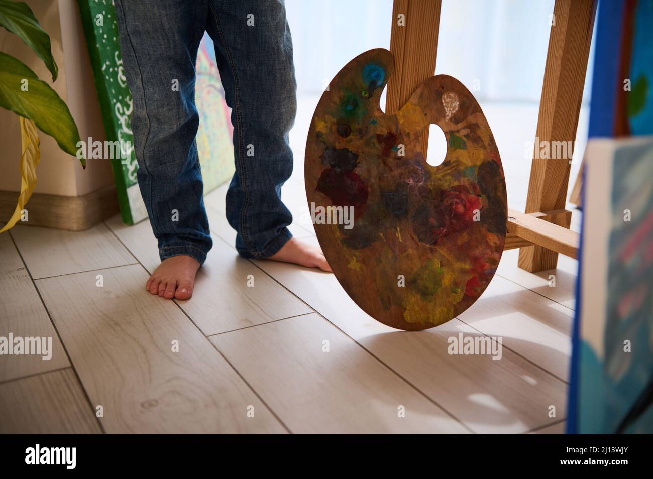 Close-up of a wooden palette with paints leaning on a wooden easel on ...