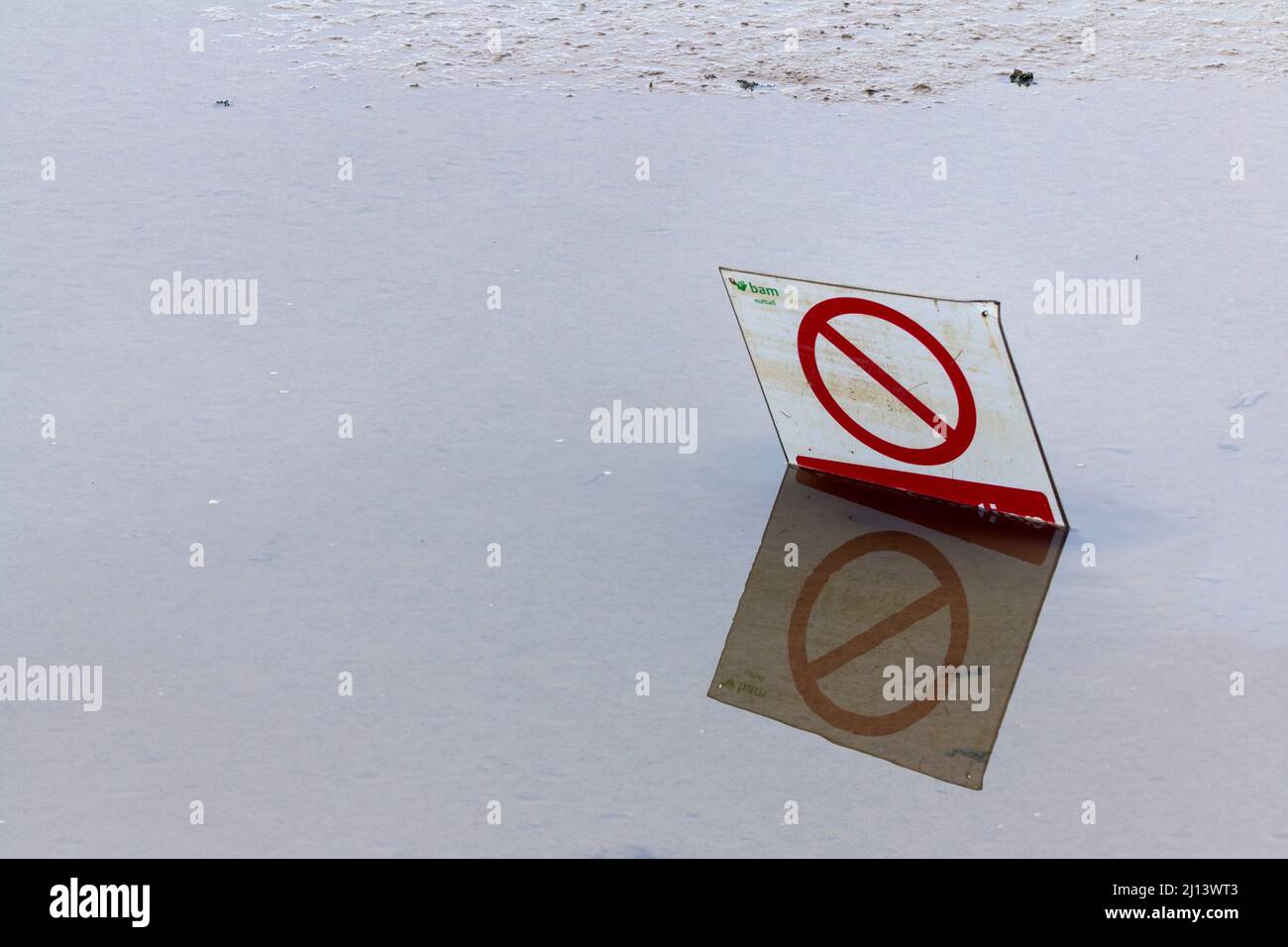 No entry sign in shallow water with reflection, red circle with ...