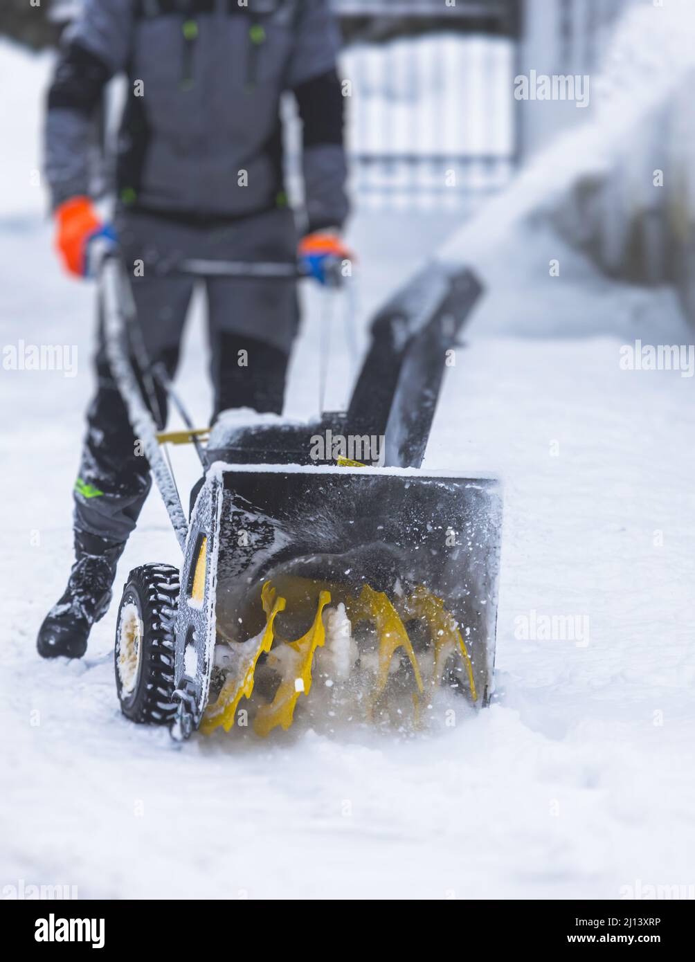 Process of removing snow with portable blower machine, worker dressed in overall workwear with ...