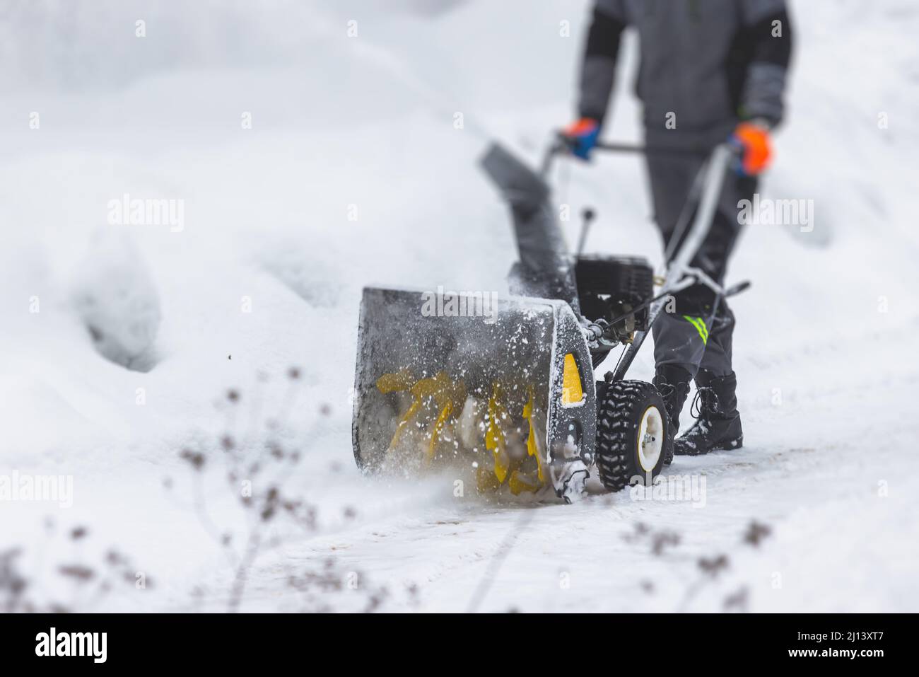 Process of removing snow with portable blower machine, worker dressed in overall workwear with ...