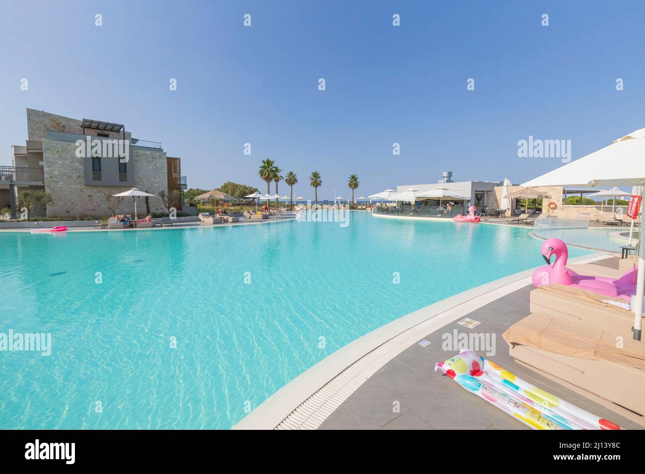 Beautiful view of outdoor pool and people on sun beds in pool on sunny ...