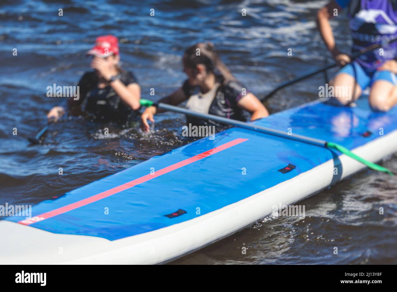 Group of young SUP surfers fall from stand up paddle board, women ...