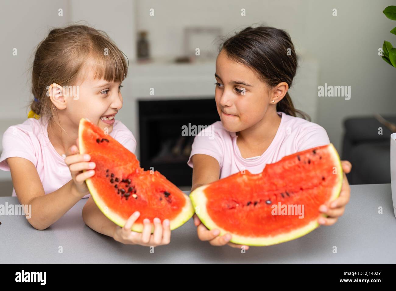 Two kids eating one slice of watermelon. Kids eat fruit outdoors ...