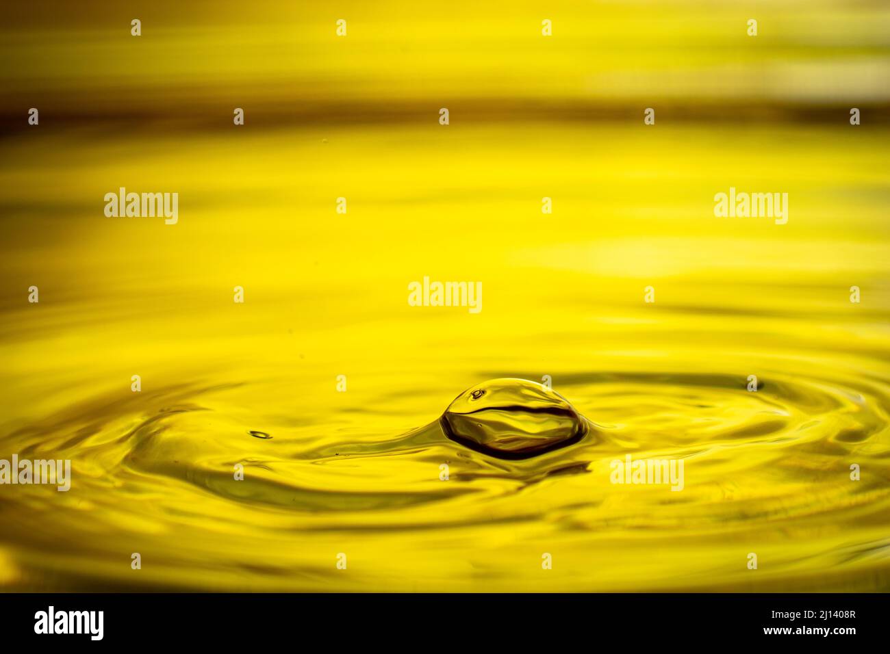 A drop splashing in yellow water Stock Photo - Alamy