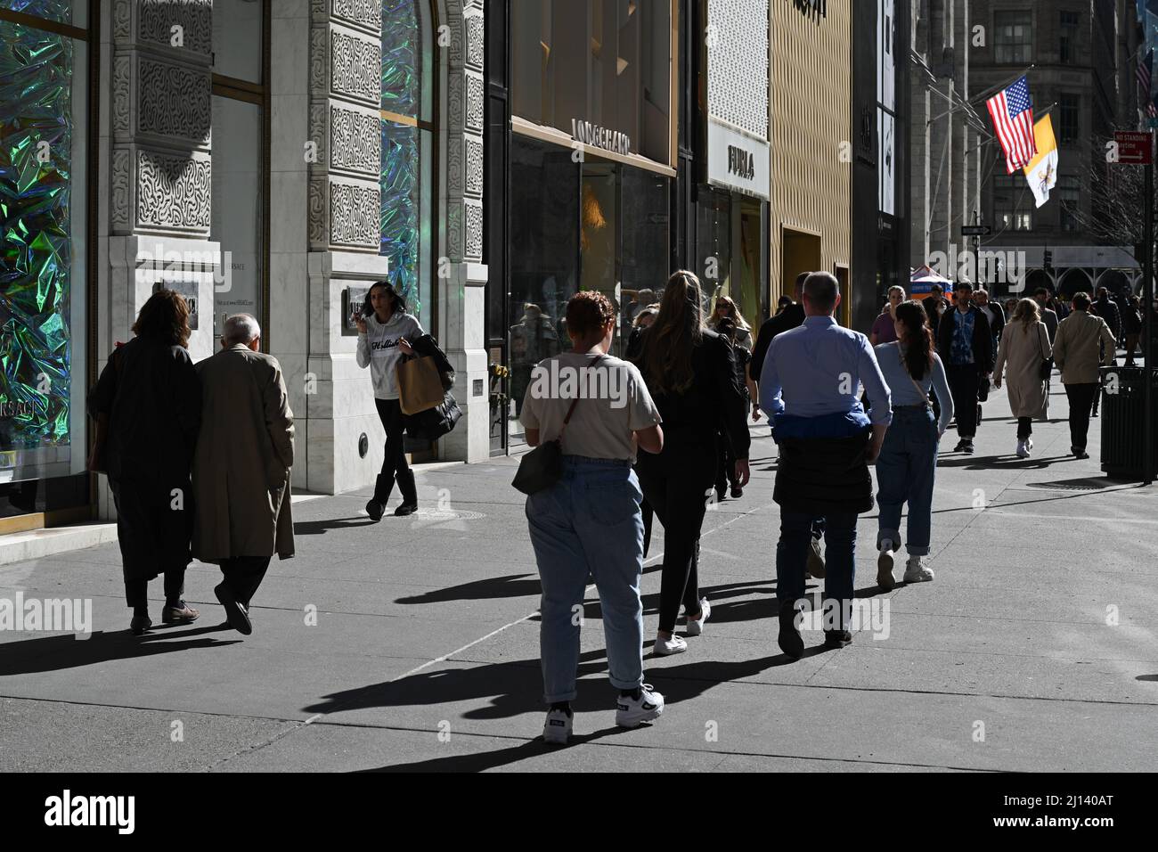 People walk past stores on Fifth Avenue in Midtown Manhattan in New ...