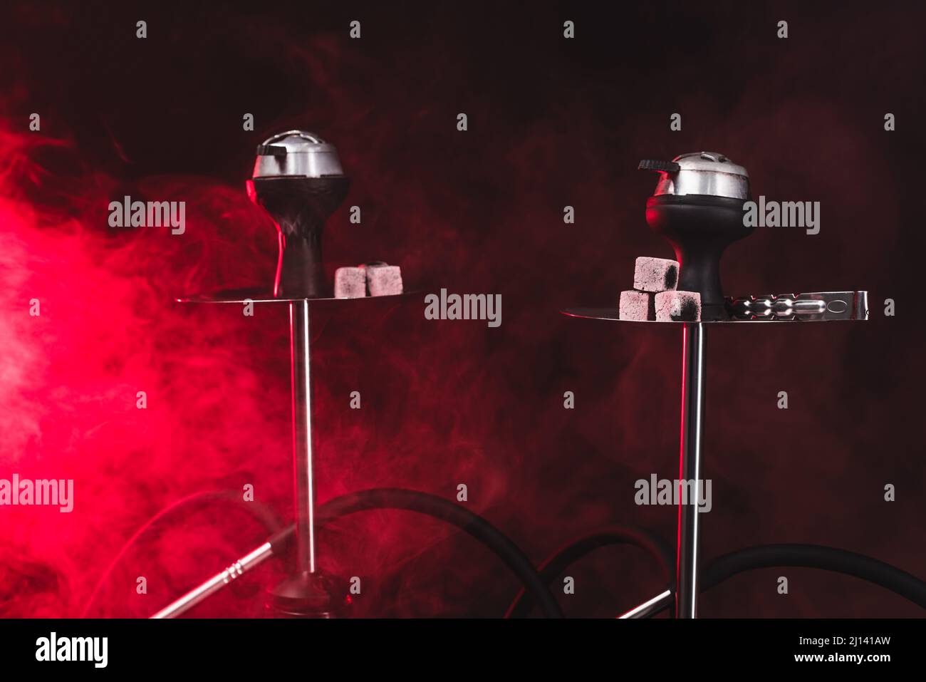 Hookahs with coals on black background with red smoke Stock Photo - Alamy
