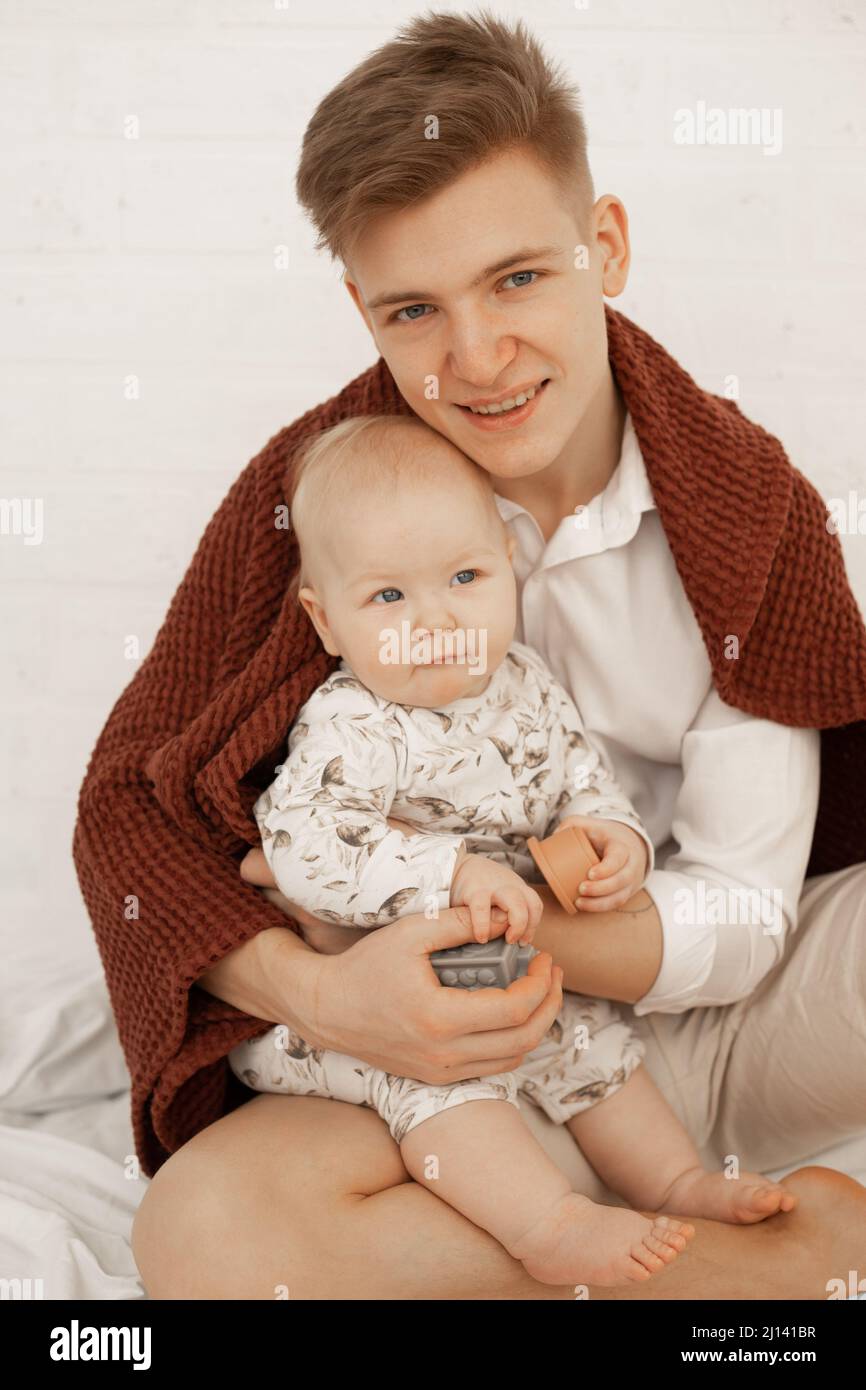 Vertical photo of young smiling man dad holding baby and toys, weekend ...