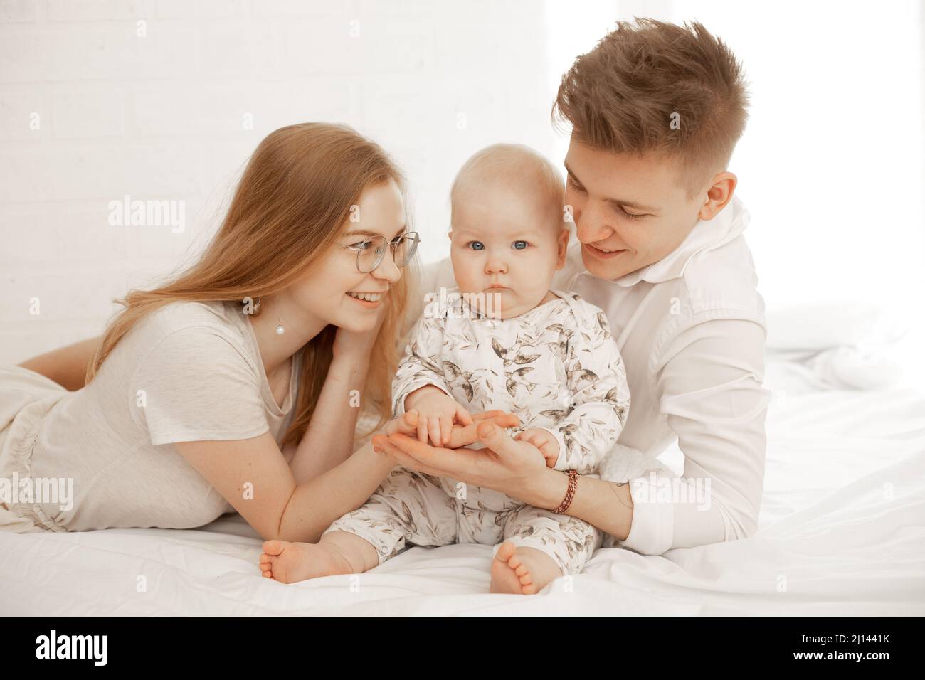 Happy joyful satisfied family of woman, man and infant baby lying in ...