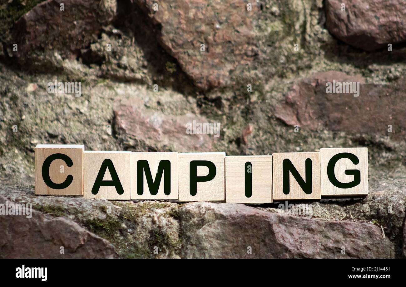 Camping word on a wooden cube sign with a blurry background of a ...