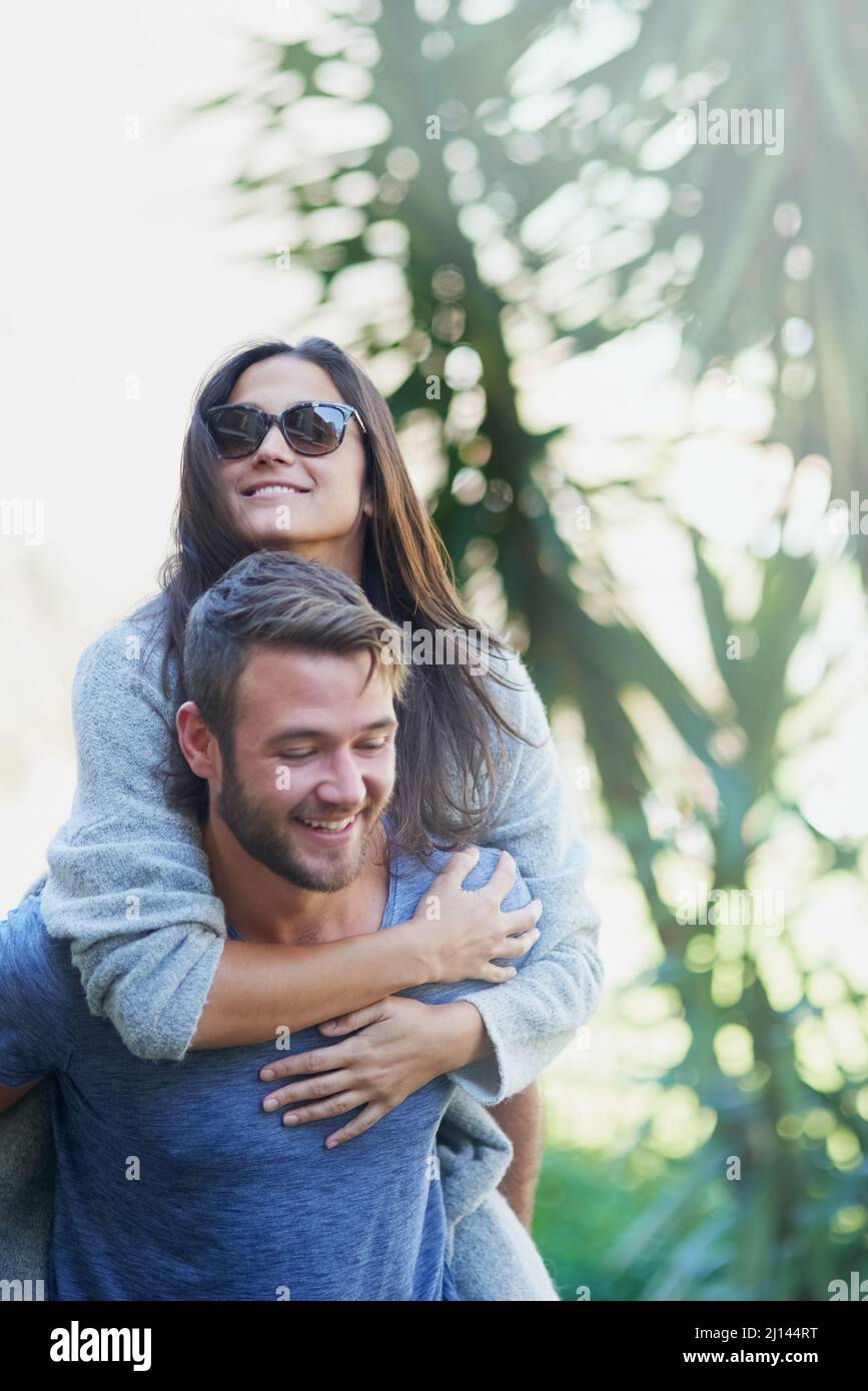 Fun and in love. Shot of a young man giving his girlfriend a piggyback ...