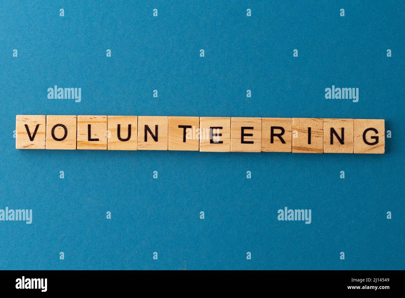 Volunteering background. Phrase from wooden letters. Top view words ...