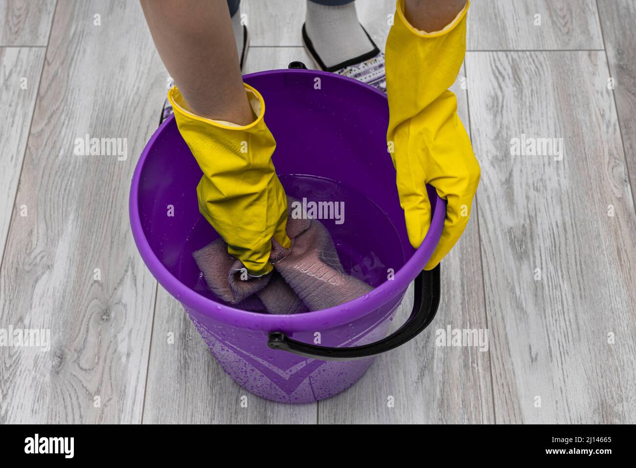 a hand in a rubber glove wets a rag in a bucket of water. High quality ...