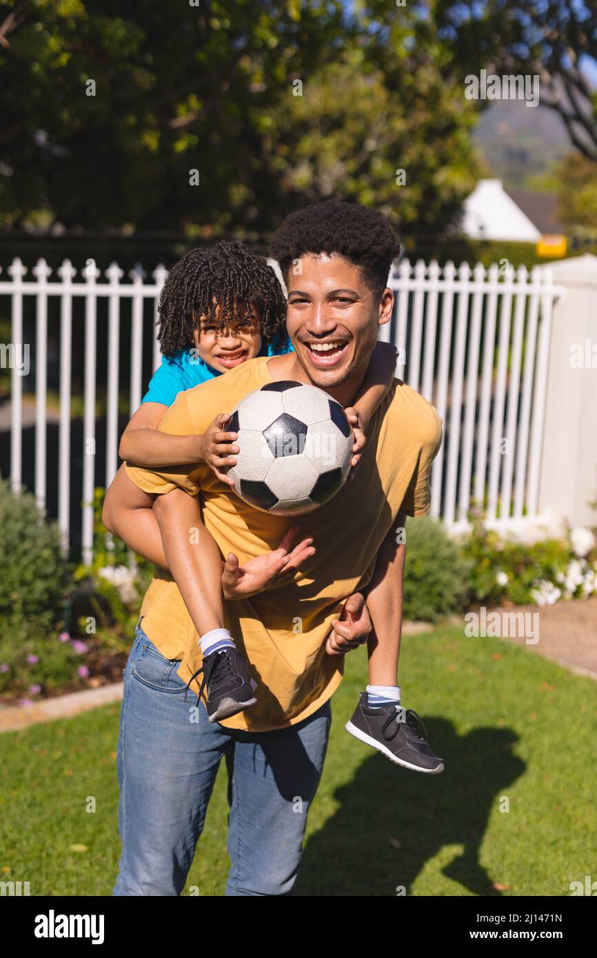 Portrait of happy hispanic father giving piggyback ride to son holding ...