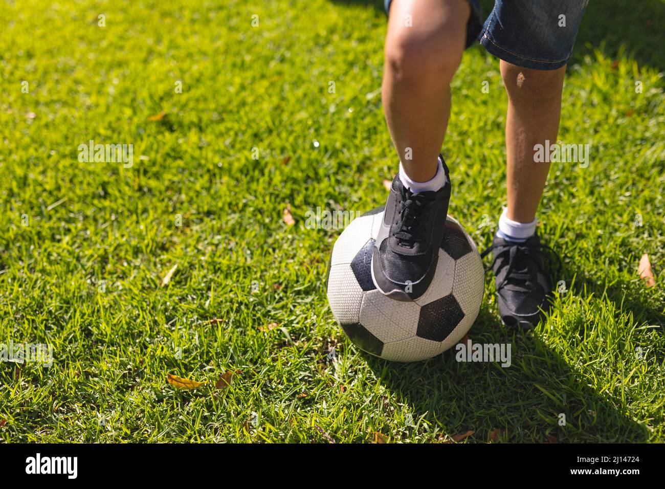 High angle low section of hispanic boy stepping on soccer ball at ...
