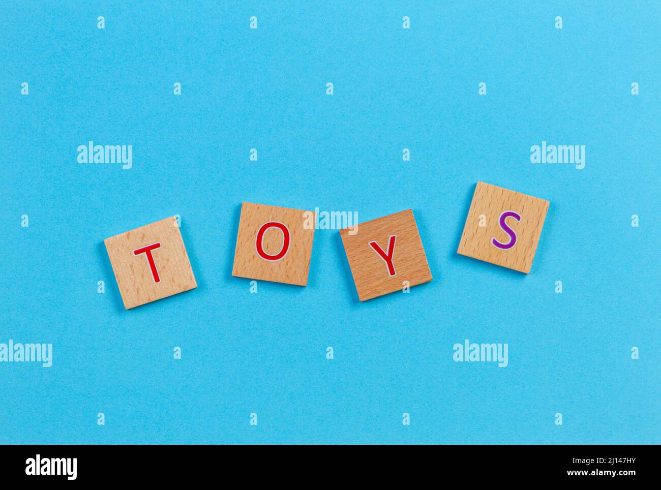 The word TOYS, spelt with wooden letter tiles over blue background. Top ...