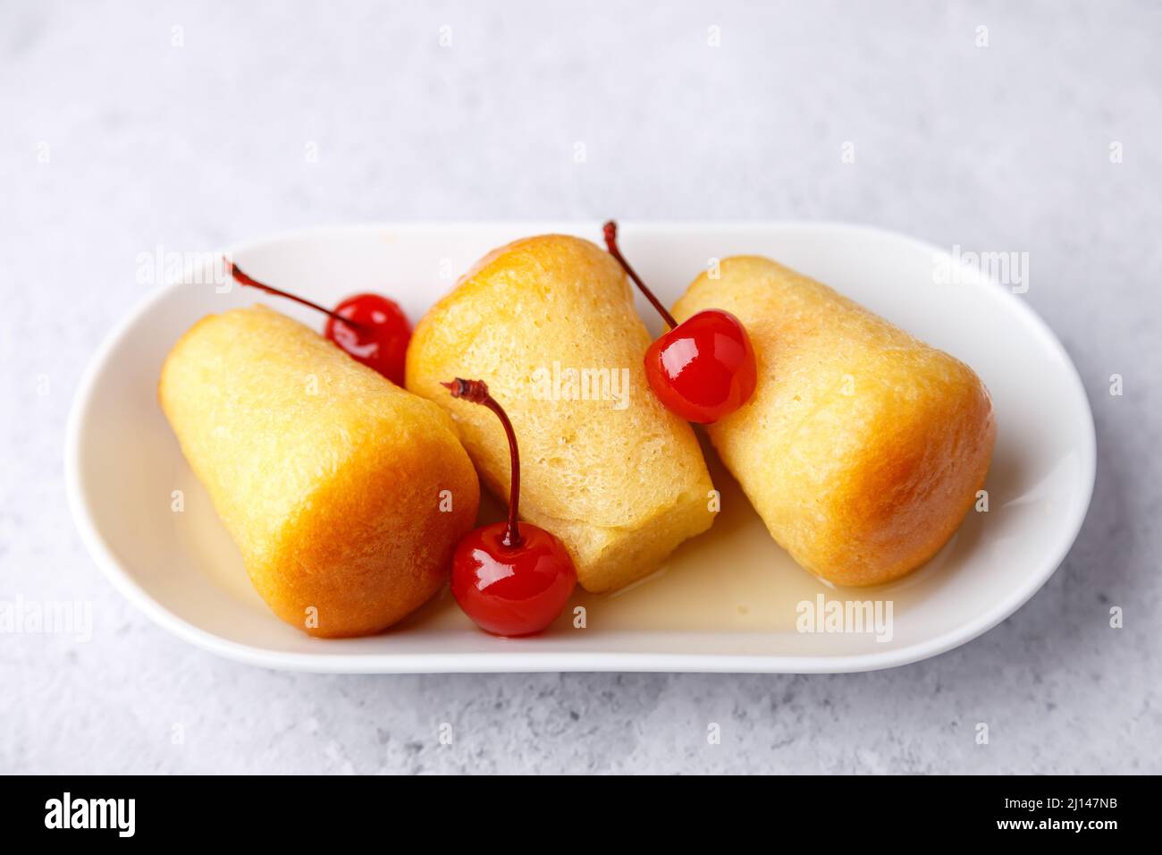 Neapolitan Rum baba (or baba au rum) on a white plate with a cocktail ...