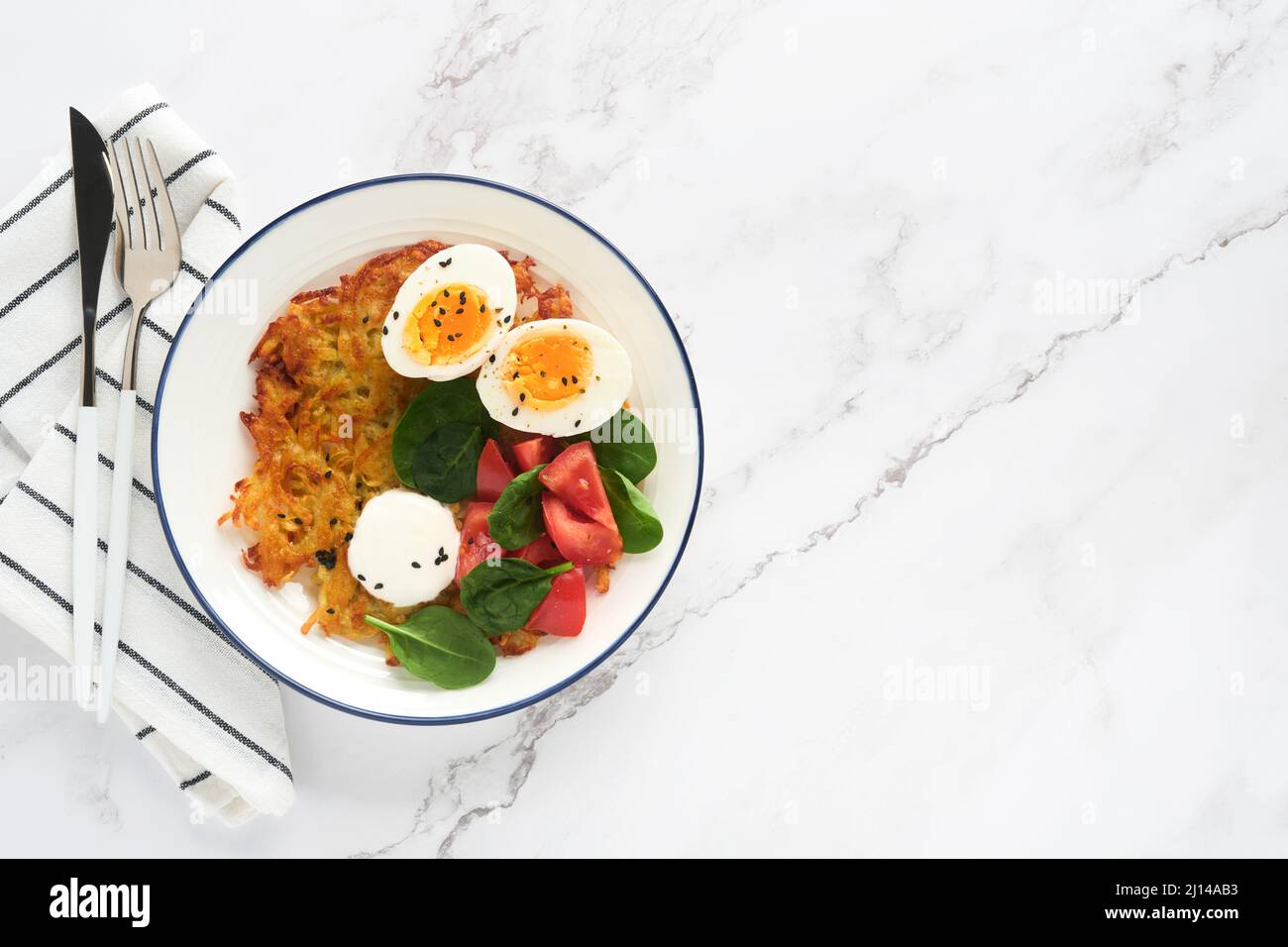 Breakfast. Potatoes latkes with sour cream, spinach salad, tomatoes and ...