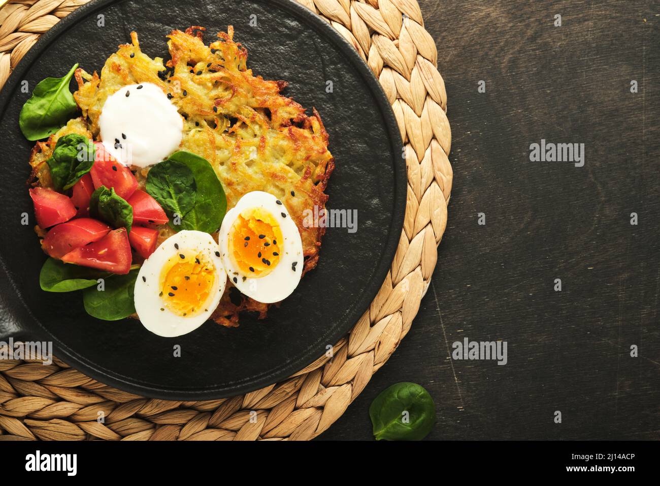 Potatoes latkes with sour cream, spinach salad, tomatoes and boiled ...