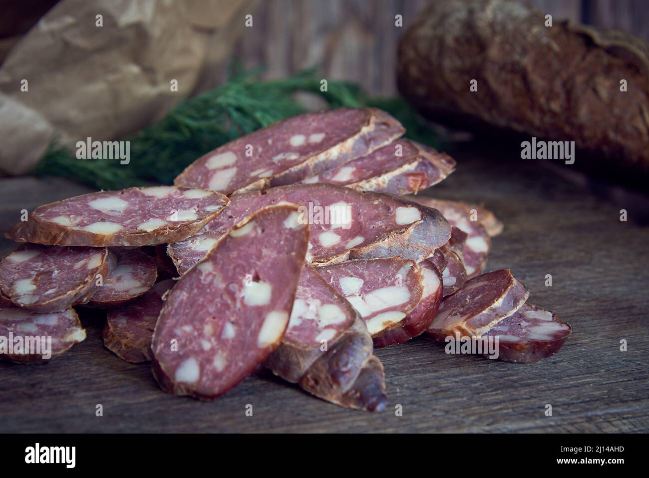 Smoked sausage, cut into pieces lies on a wooden cutting board. Food ...