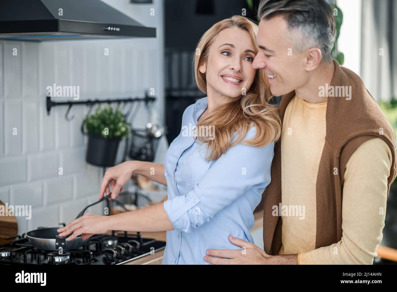 A couple hugging in the kitchen and looking happy Stock Photo - Alamy