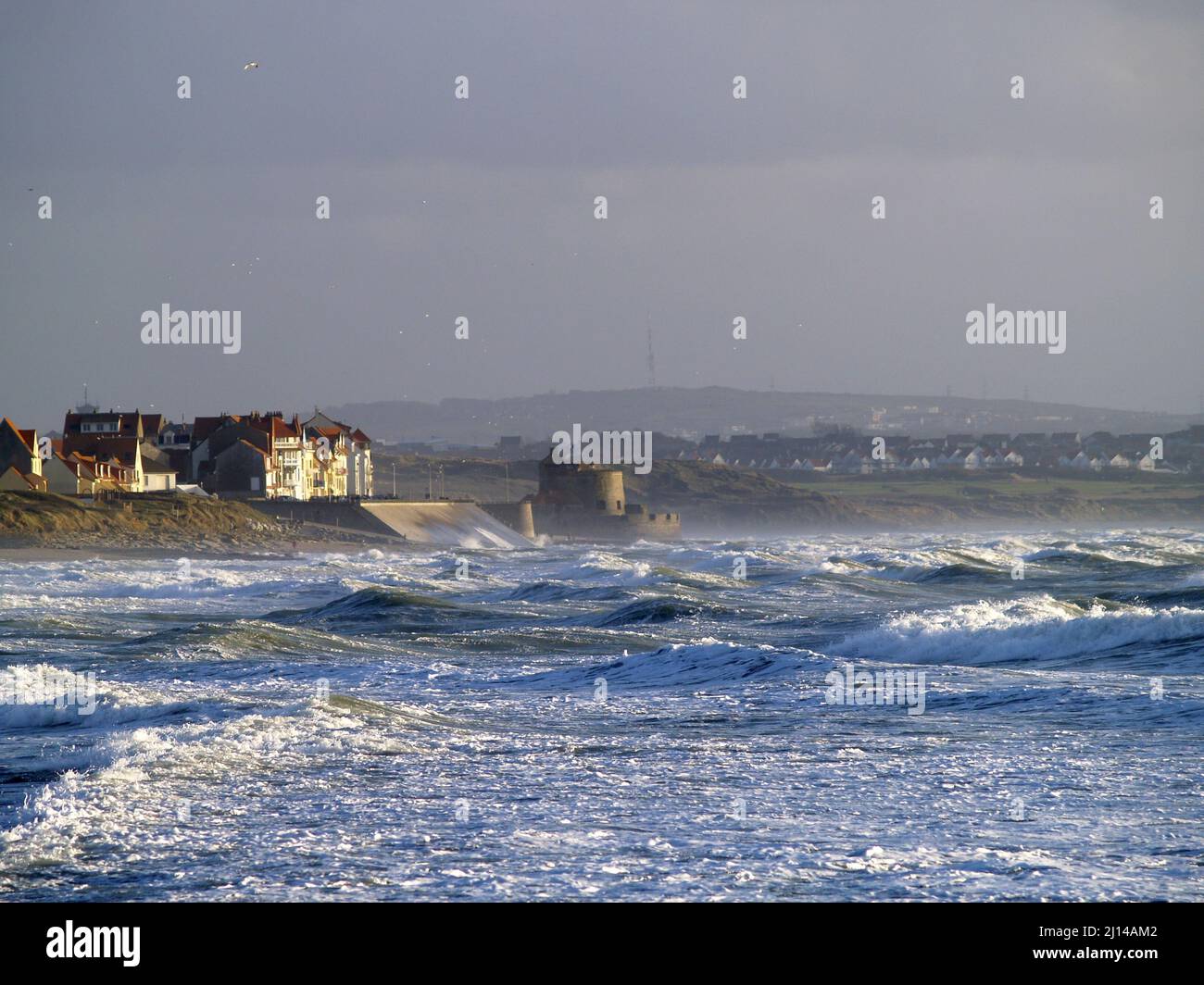 View of a sea waves moving under the golden sun with a rural area and ...