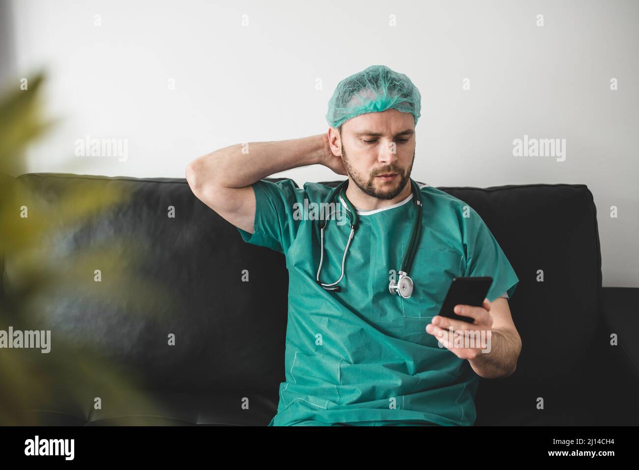 Doctor using phone in the resting room Stock Photo - Alamy