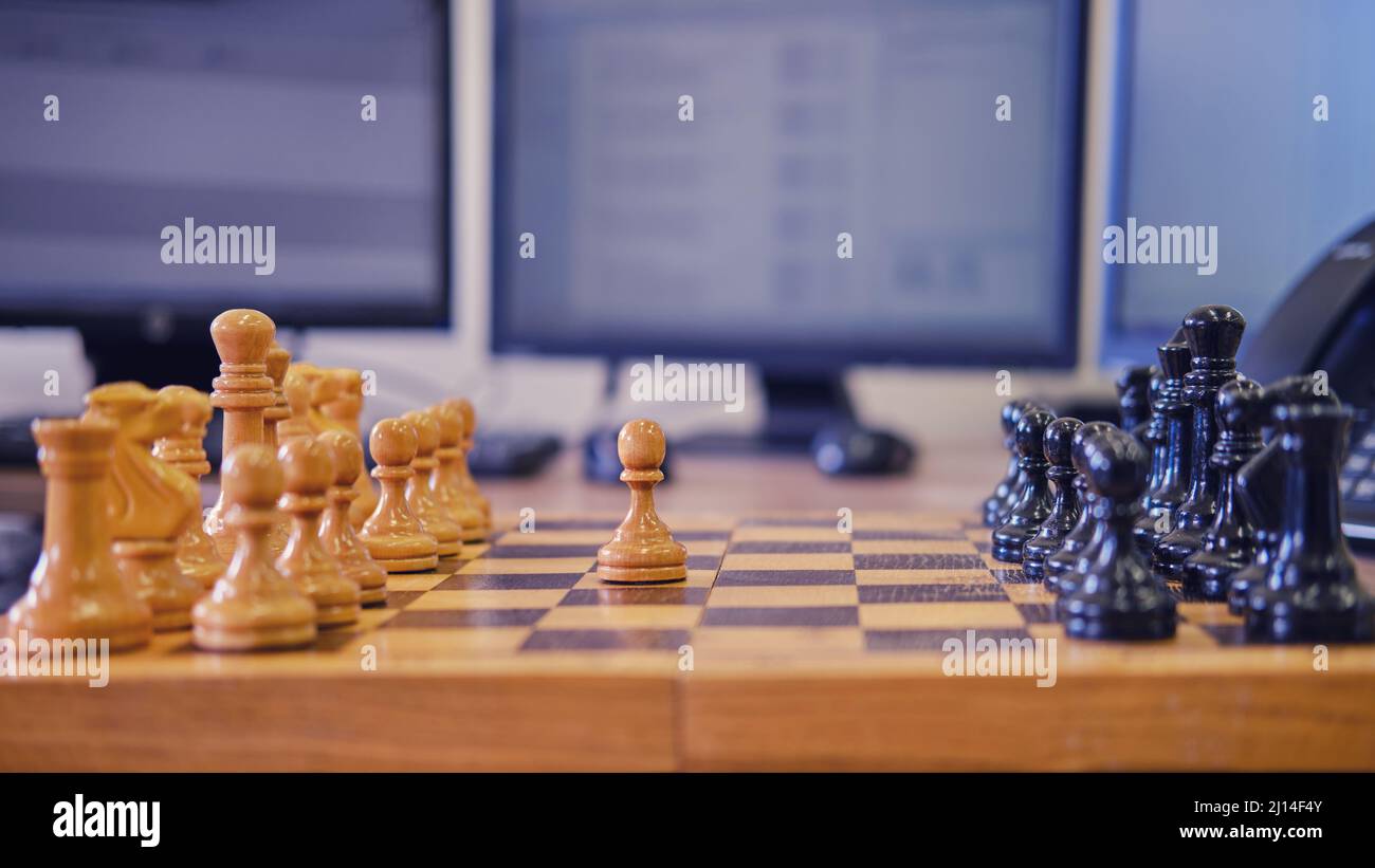A chessboard with chess pieces placed on an office table near computer ...