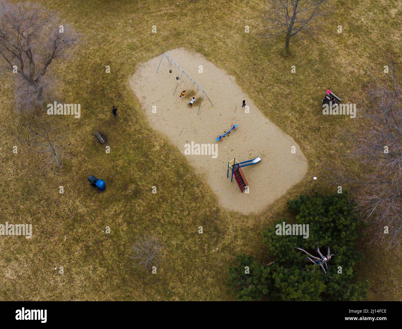 Drone shot of a playground in the field surrounded by a few leafless ...