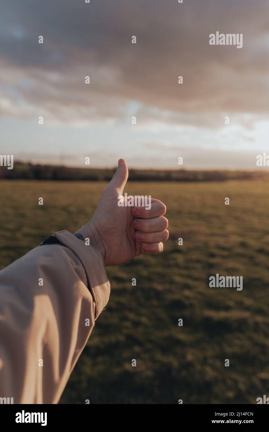 Vertical shot of a man's hand showing thumb up in the background of ...