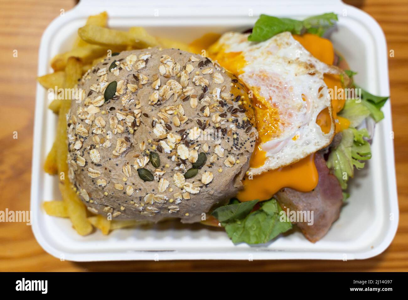 Big burger with seeds bread, fried egg, bacon, lettuce and french fries ...