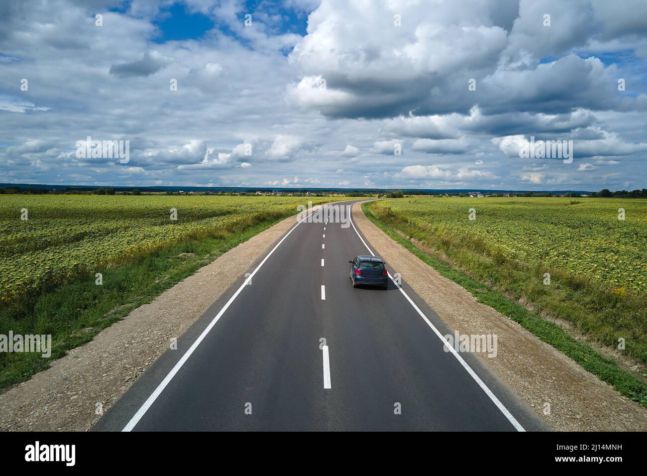 Aerial view of intercity road between green agricultural fields with ...