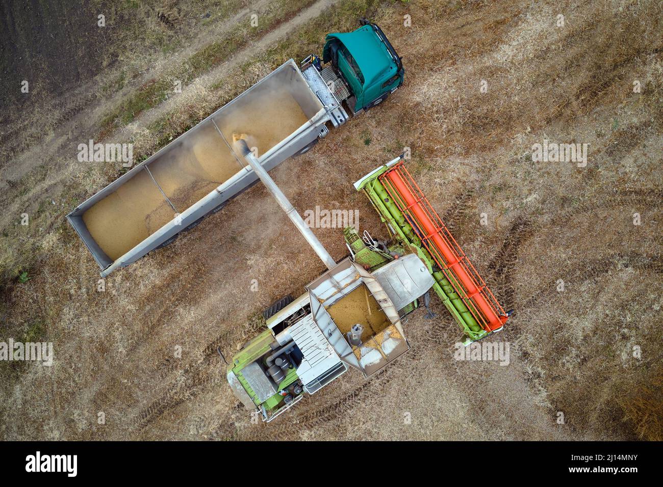 Aerial view of combine harvester unloading grain in cargo trailer ...