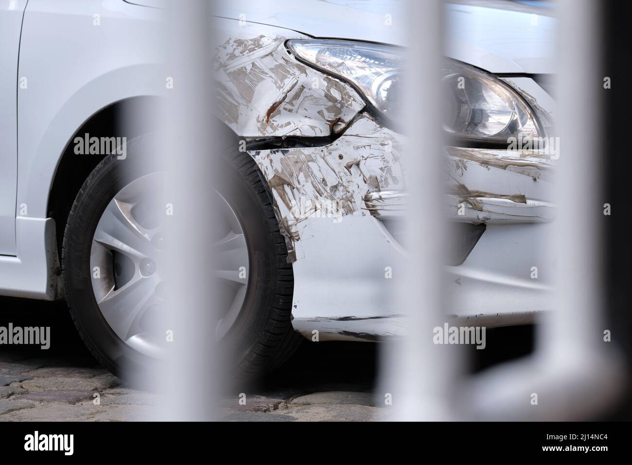Dented car with damaged fender parked on city street side. Road safety ...