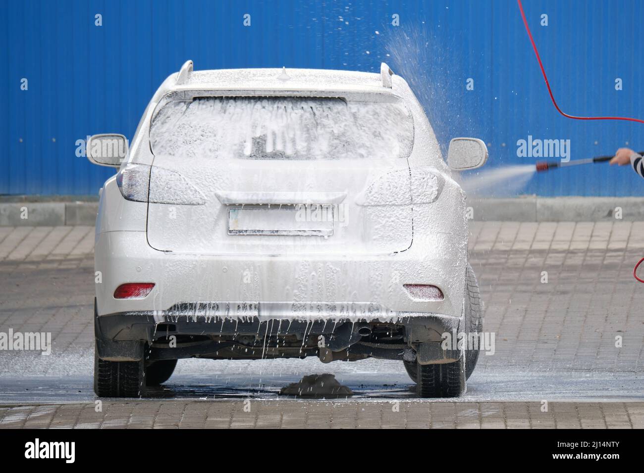 Young driver man washing his car with contactless high pressure water ...