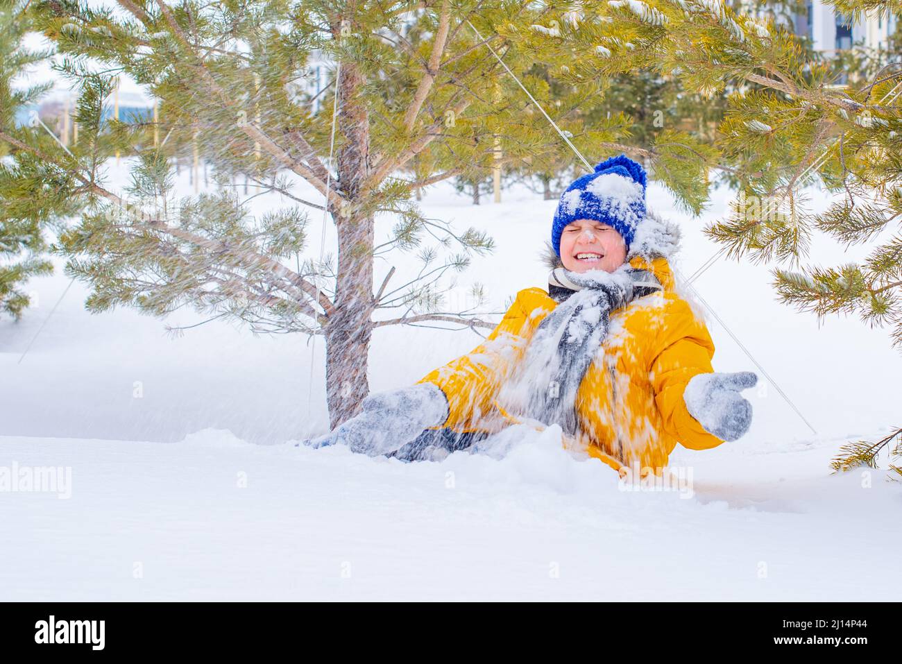 cheerful boy in a yellow jacket in the snow Stock Photo - Alamy