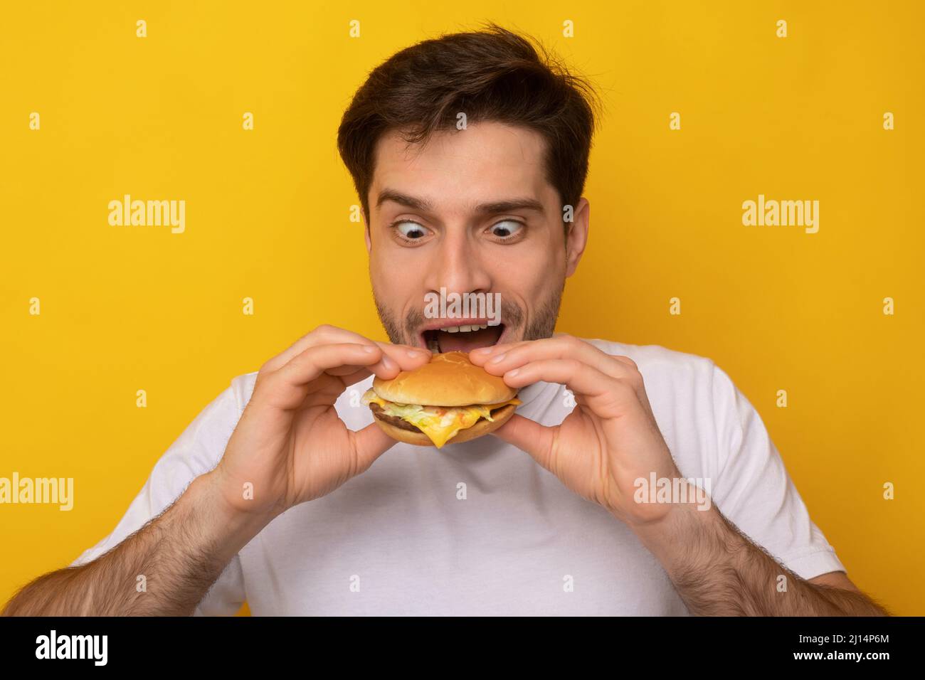 Funny Guy Holding Burger Biting Sandwich At Studio Stock Photo - Alamy