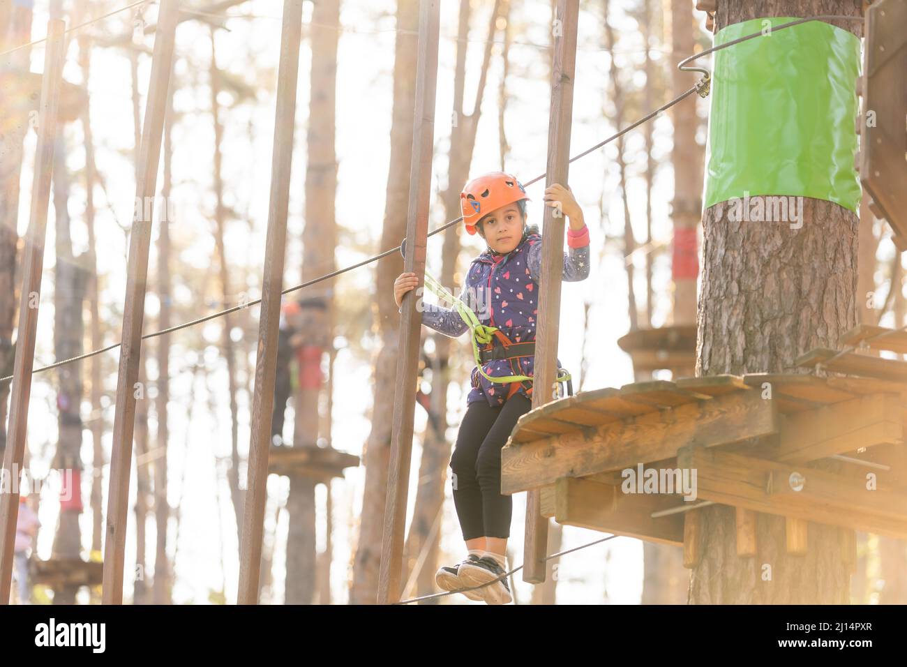 Happy school girl enjoying activity in a climbing adventure park on a ...
