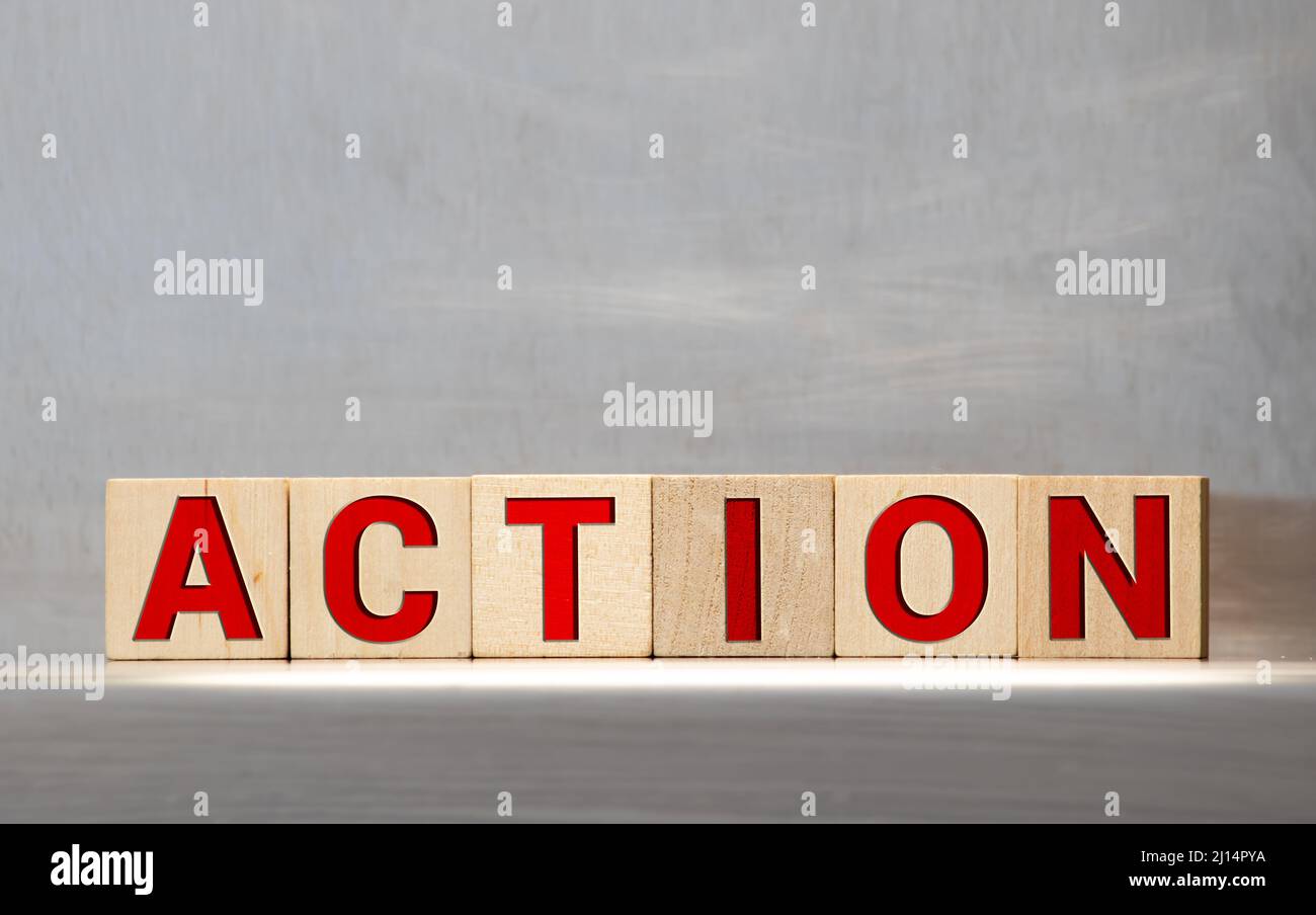 An action single word on wooden block with vintage soft blue bokeh ...